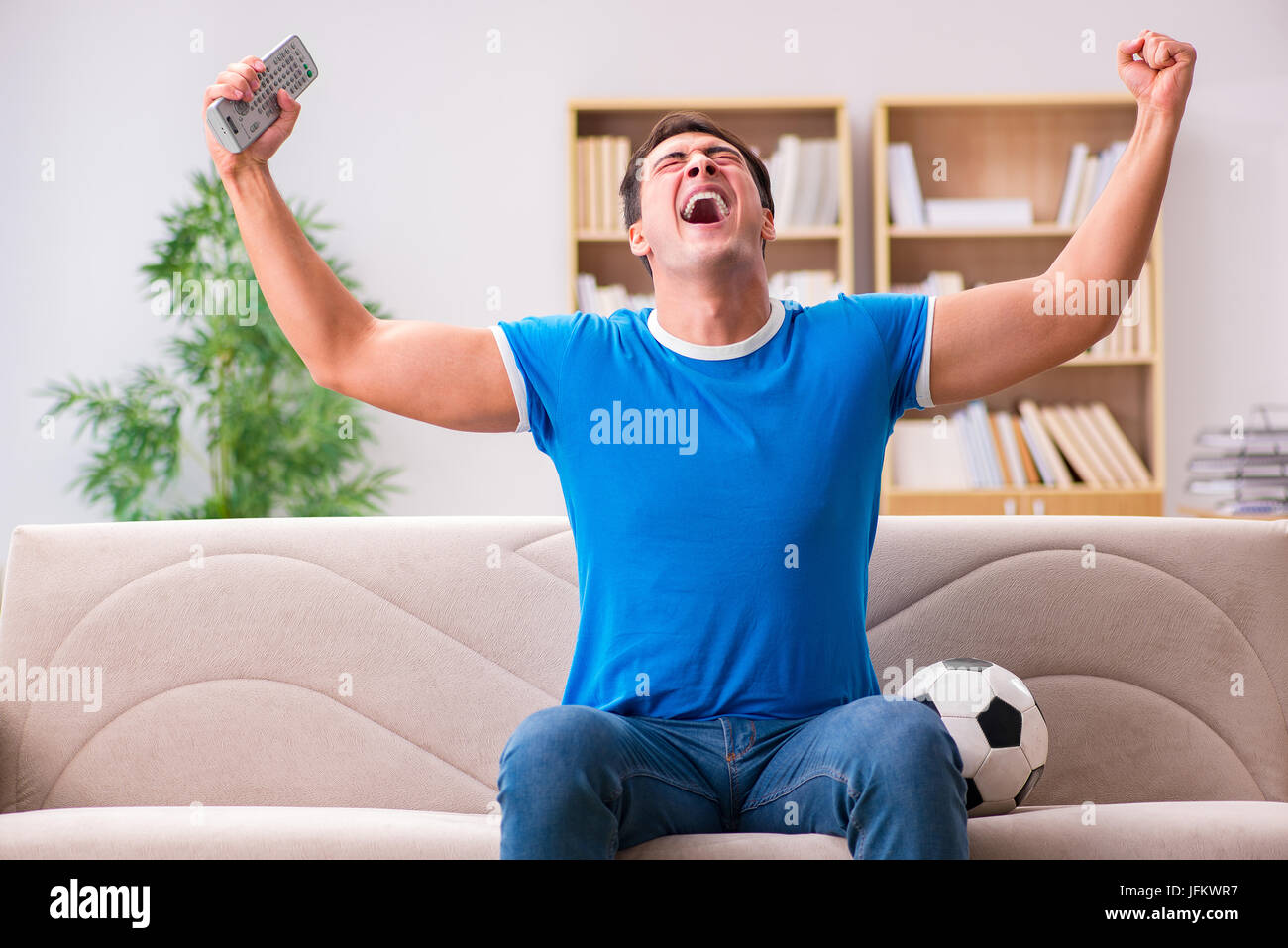 Man watching football at home sitting in couch Stock Photo - Alamy
