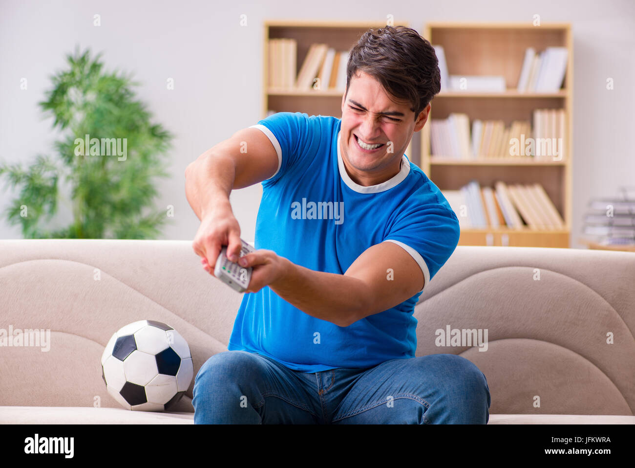 Man watching football at home sitting in couch Stock Photo - Alamy