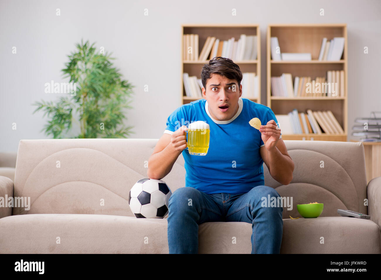 Man watching football at home sitting in couch Stock Photo - Alamy