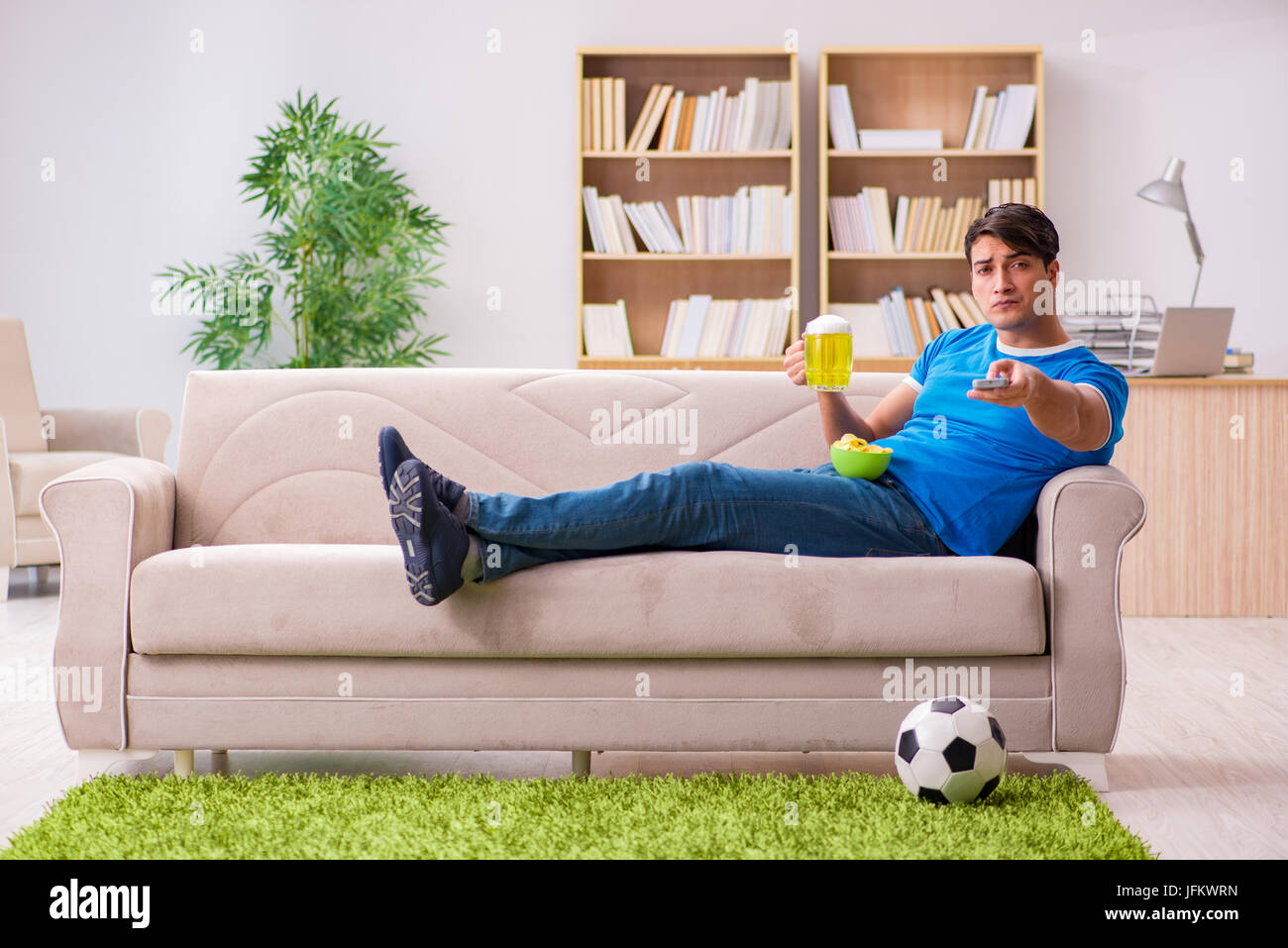 Man watching football at home sitting in couch Stock Photo - Alamy