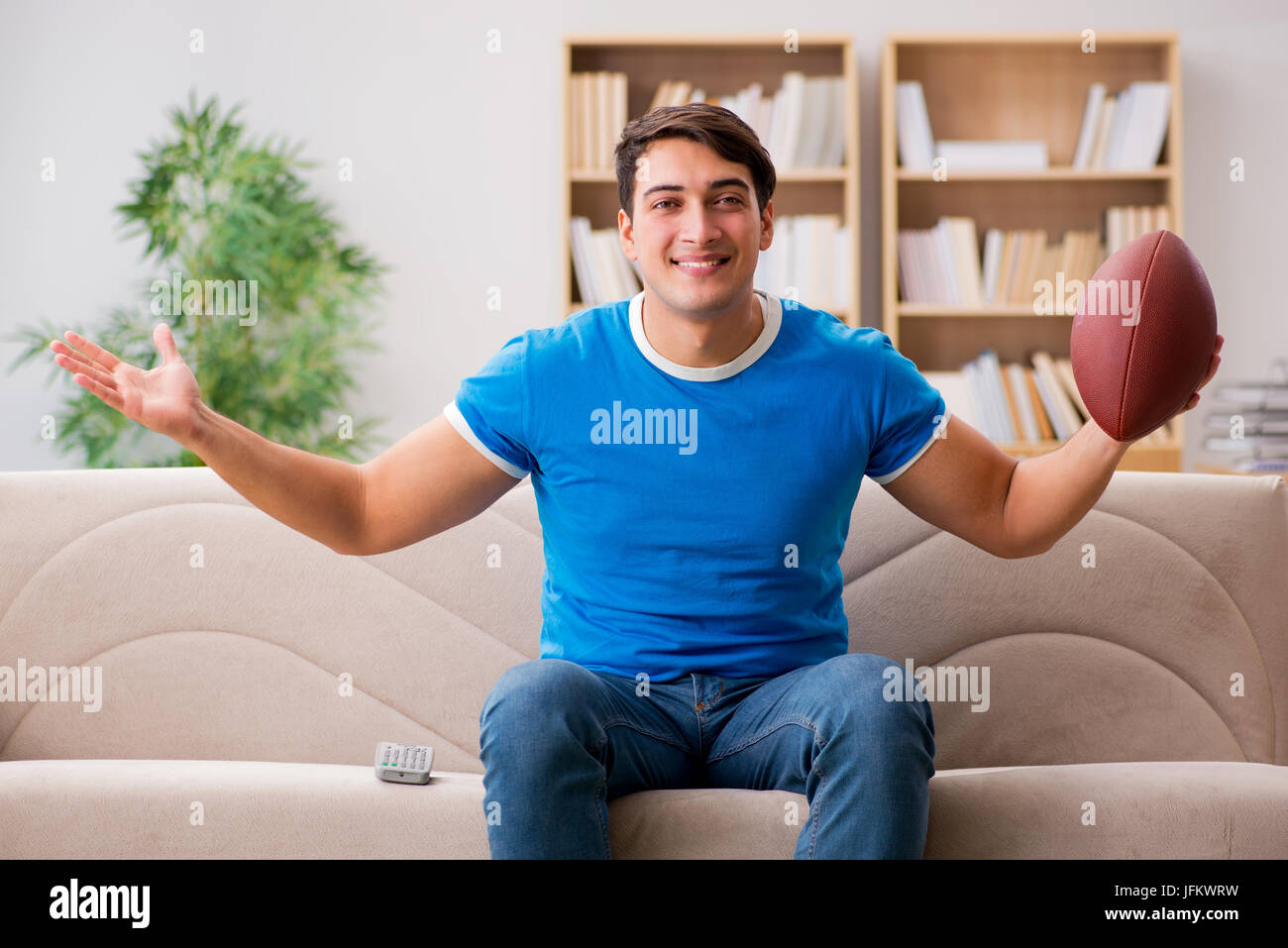 Man watching football at home sitting in couch Stock Photo - Alamy