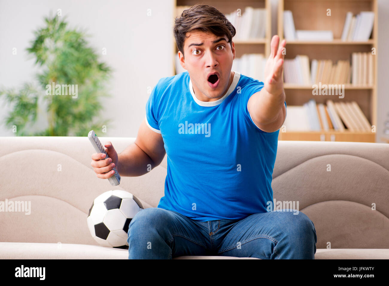 Man watching football at home sitting in couch Stock Photo - Alamy