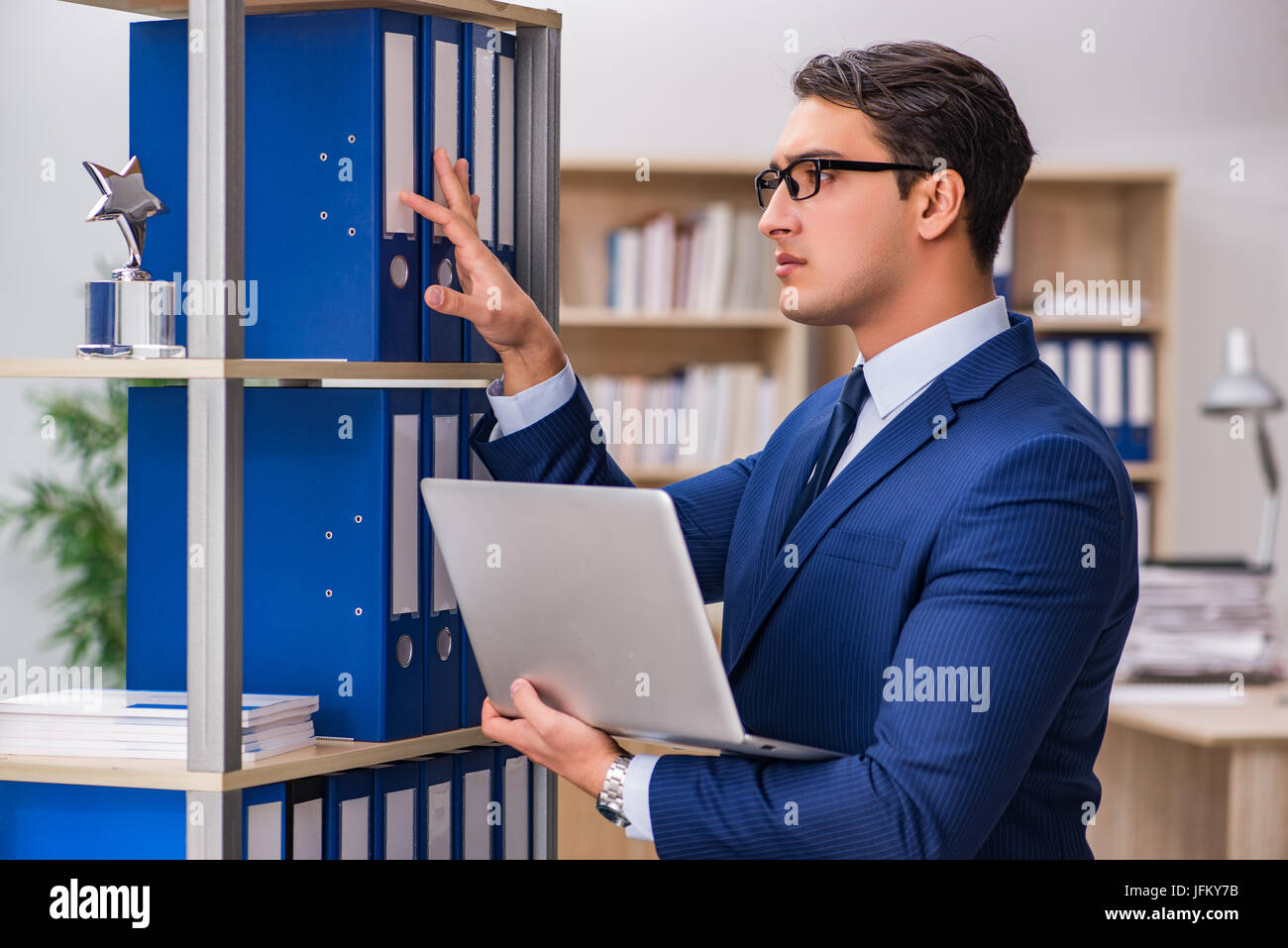 Young man standing next to the shelf with folders Stock Photo - Alamy