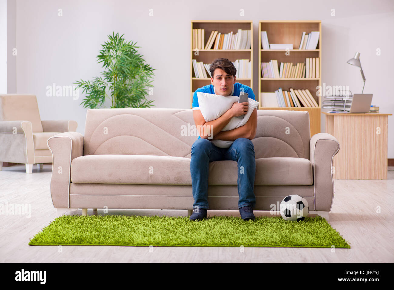 Man watching football at home sitting in couch Stock Photo - Alamy