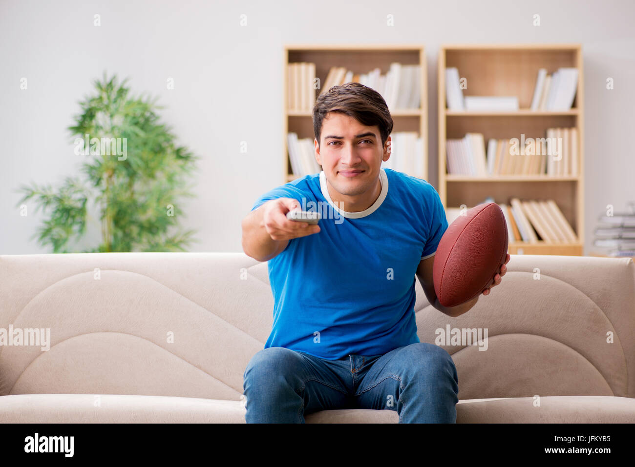 Man watching football at home sitting in couch Stock Photo - Alamy
