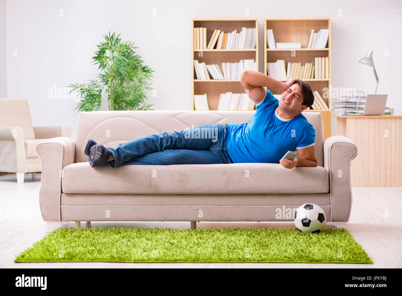 Man watching football at home sitting in couch Stock Photo - Alamy