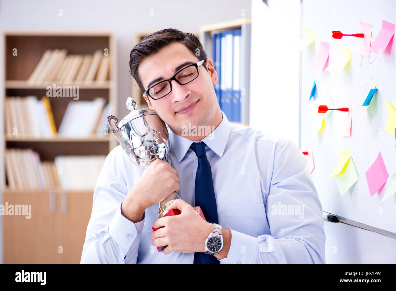 Young businessman receiving prize cup in office Stock Photo - Alamy