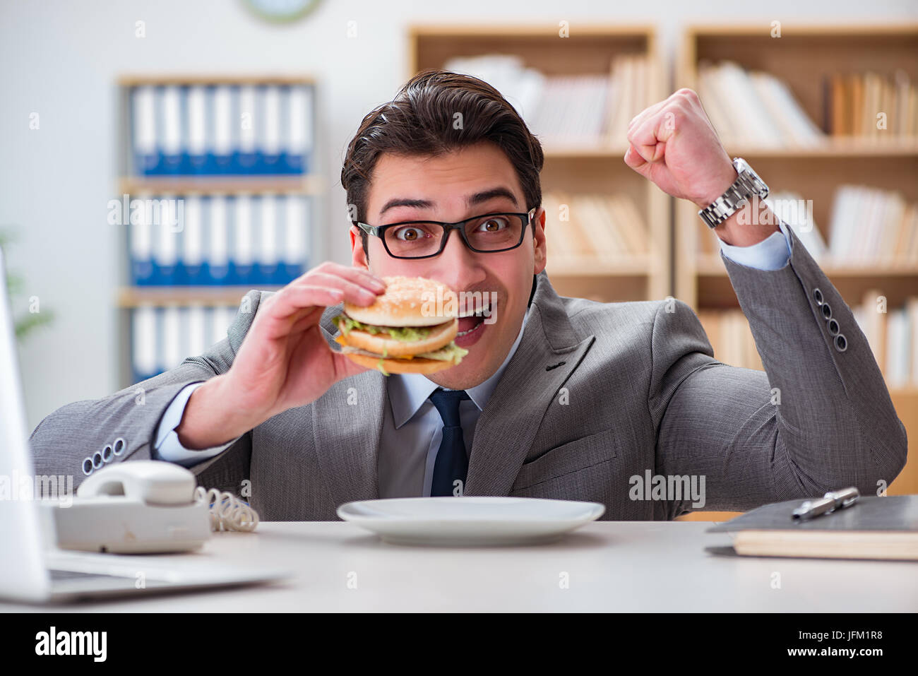 Hungry funny businessman eating junk food sandwich Stock Photo - Alamy