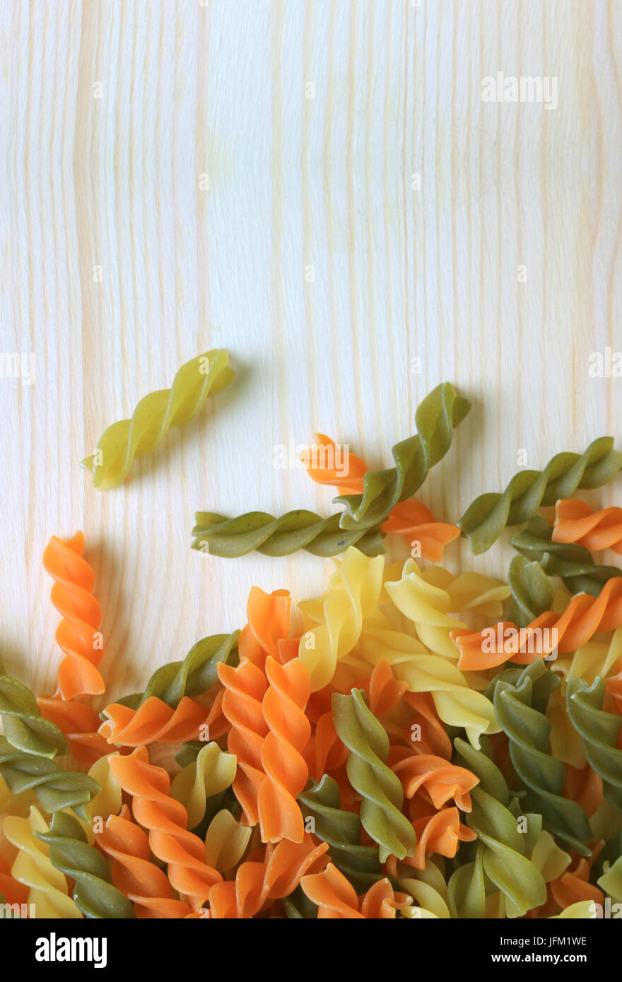 Spiral Shaped three-color fusilli pasta on natural wooden table ...