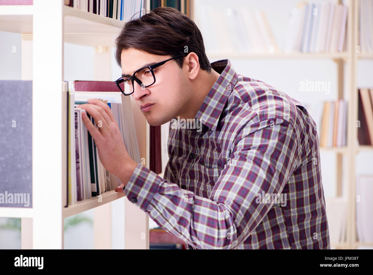 Young student looking for books in college library Stock Photo - Alamy
