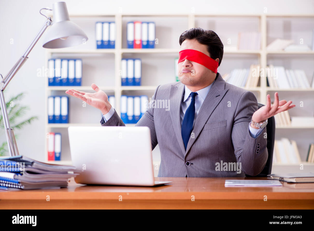 Blindfold businessman sitting at desk in office Stock Photo - Alamy