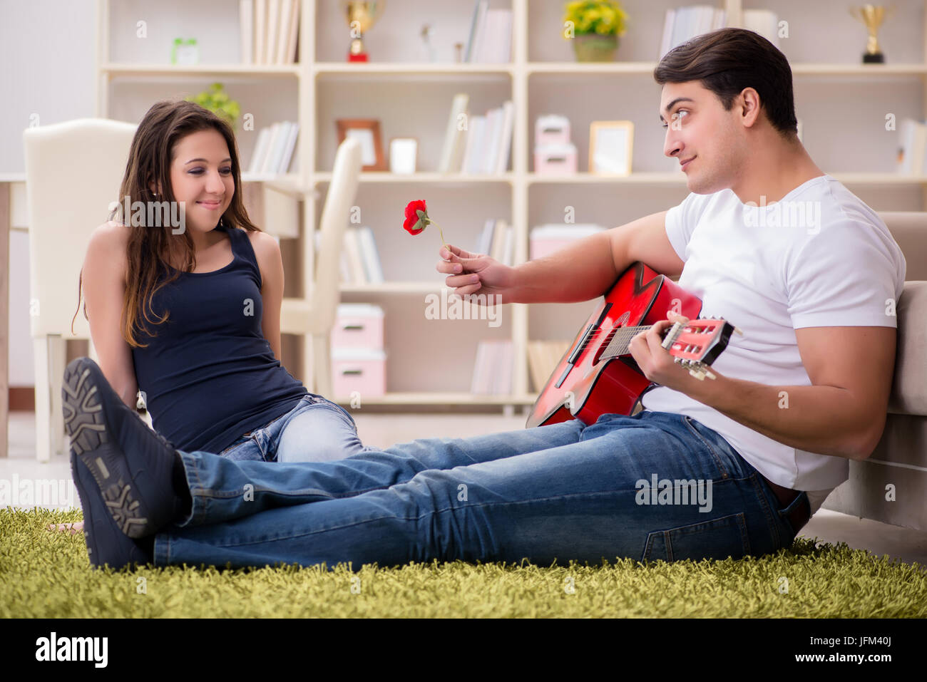 Romantic pair playing guitar on floor Stock Photo - Alamy