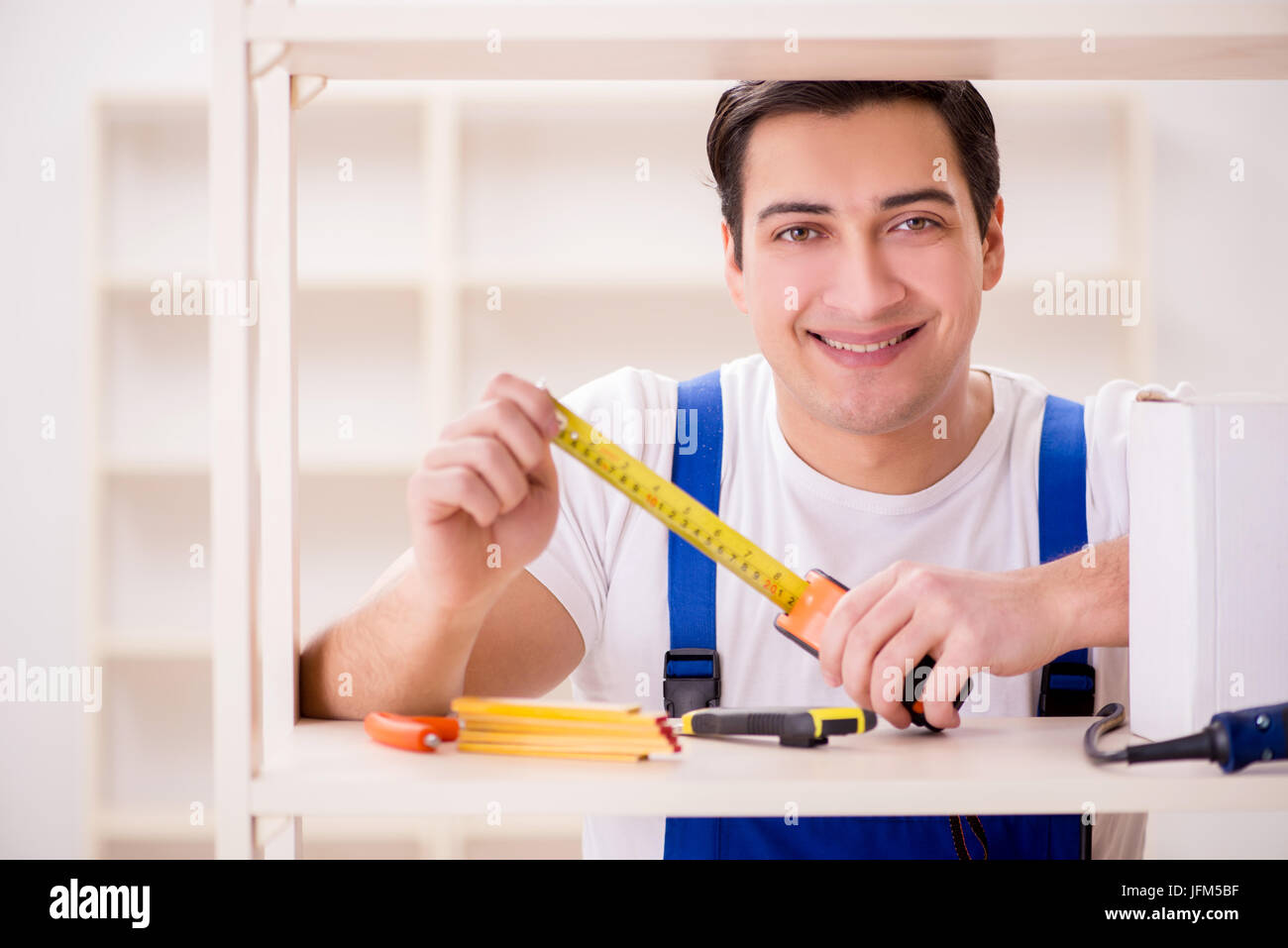 Worker man repairing assembling bookshelf Stock Photo - Alamy