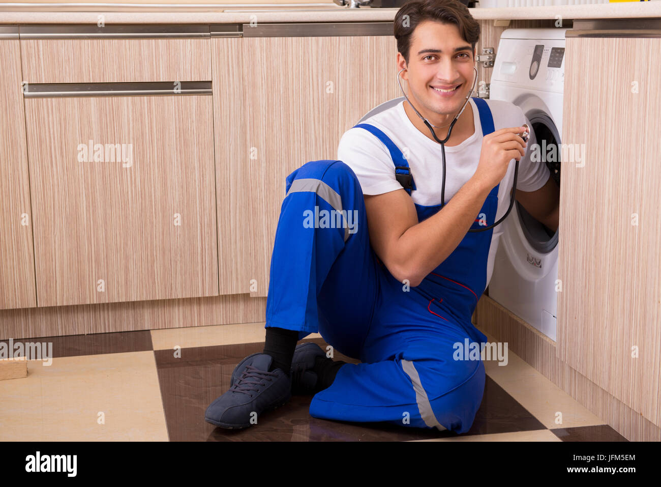 Repairman repairing washing machine at kitchen Stock Photo - Alamy