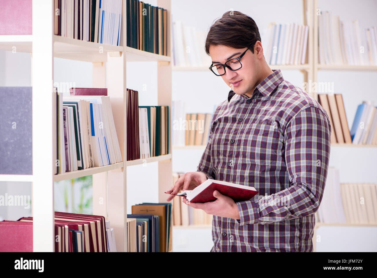 Young student looking for books in college library Stock Photo - Alamy