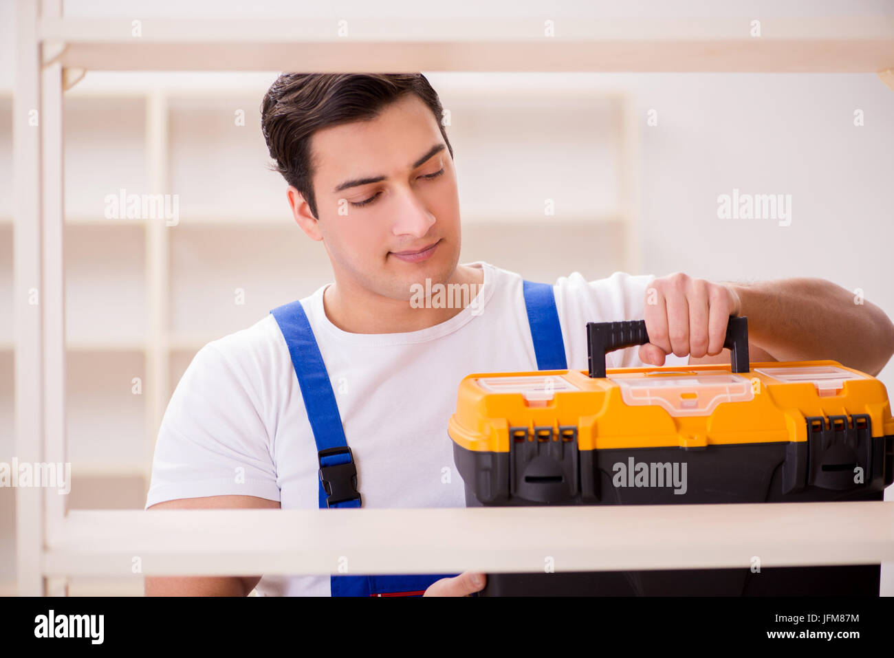 Worker man repairing assembling bookshelf Stock Photo - Alamy