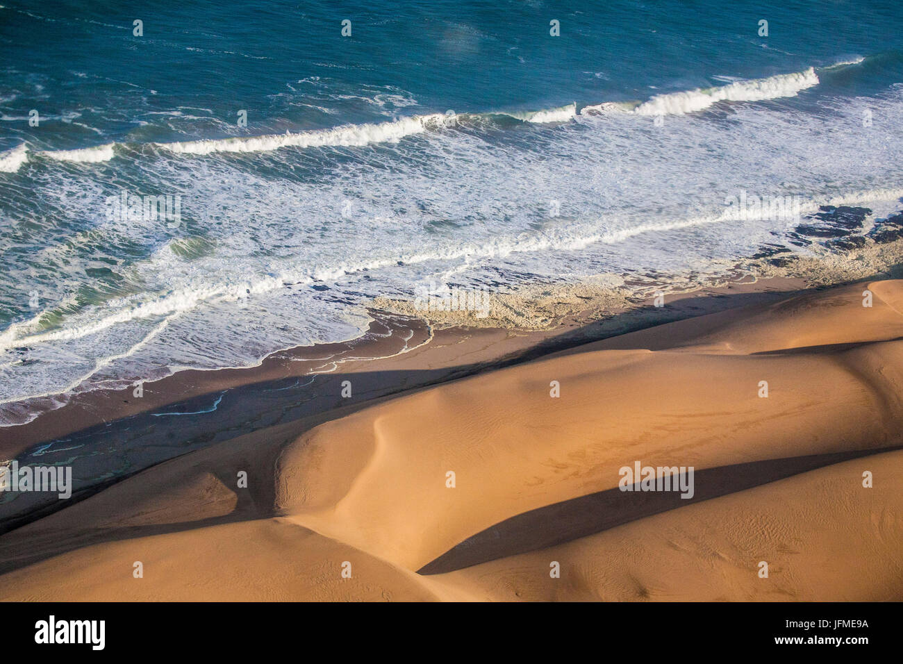 Aerial view of waves of the Atlantic Ocean crashing against the sandy ...
