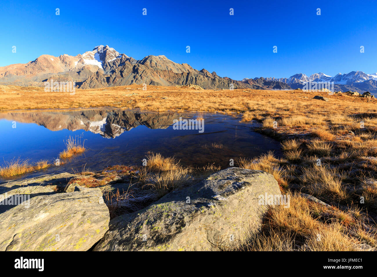 Rocky peaks of Mount Disgrazia are reflected in the alpine lake Val ...