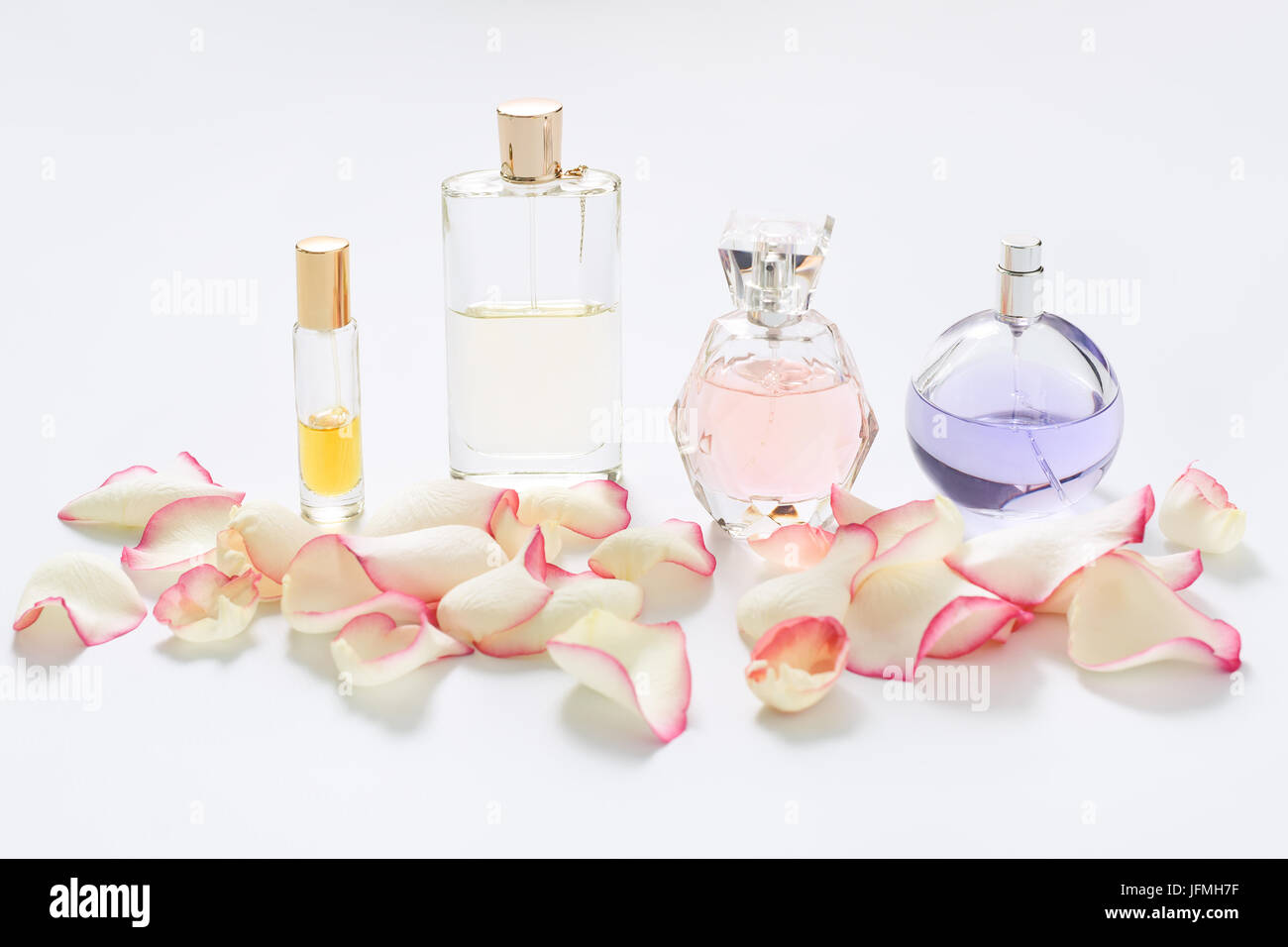 Perfume bottles with flower petals on light background. Perfumery ...