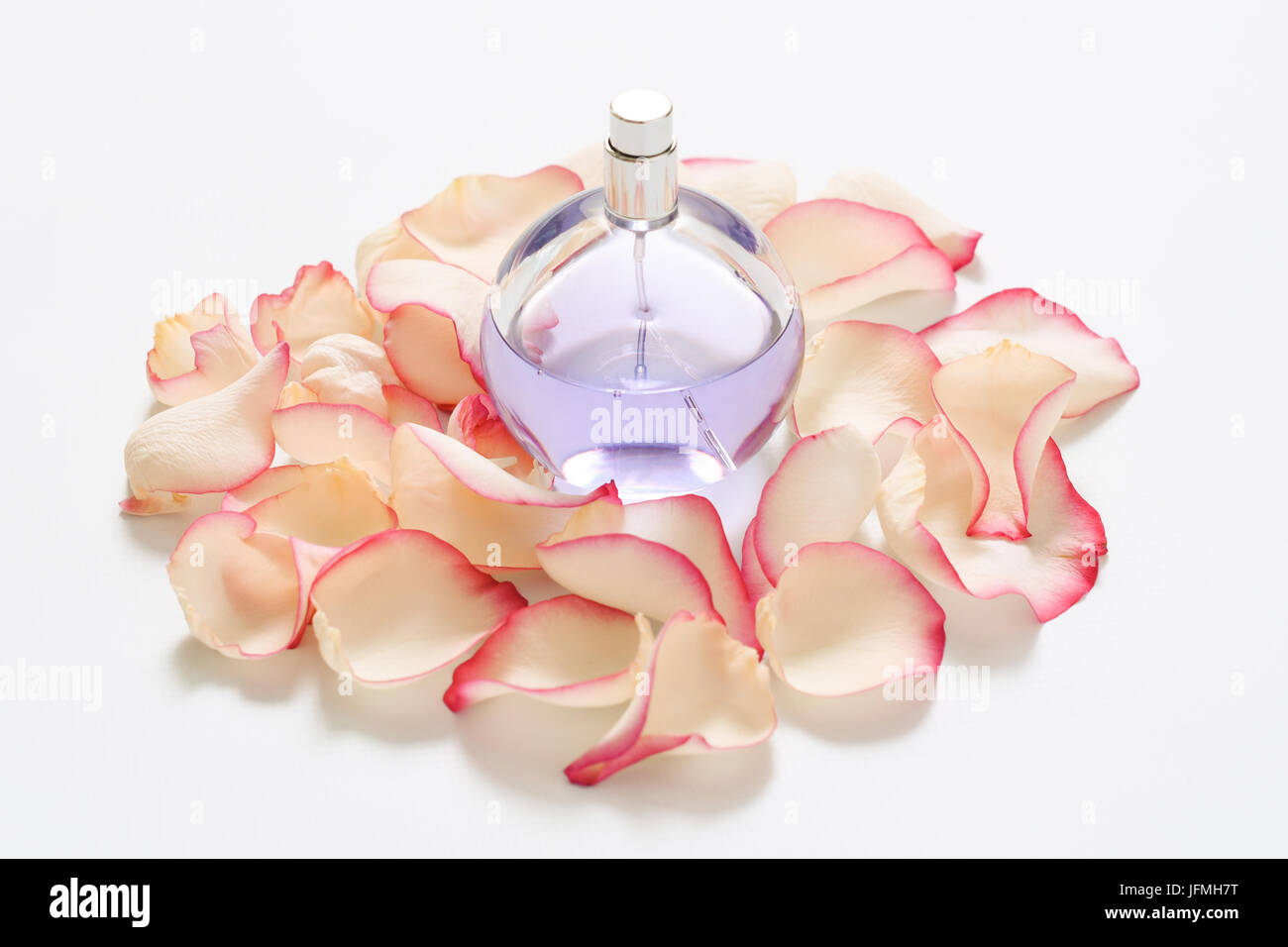 Perfume bottle with flower petals on light background. Perfumery ...