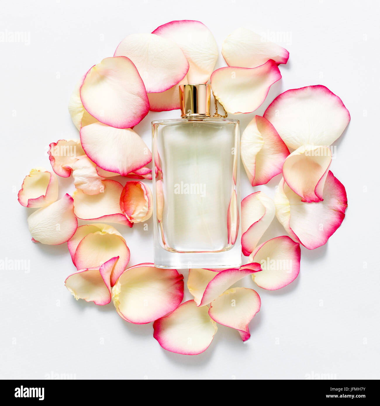 Perfume bottle with flower petals on light background. Perfumery ...