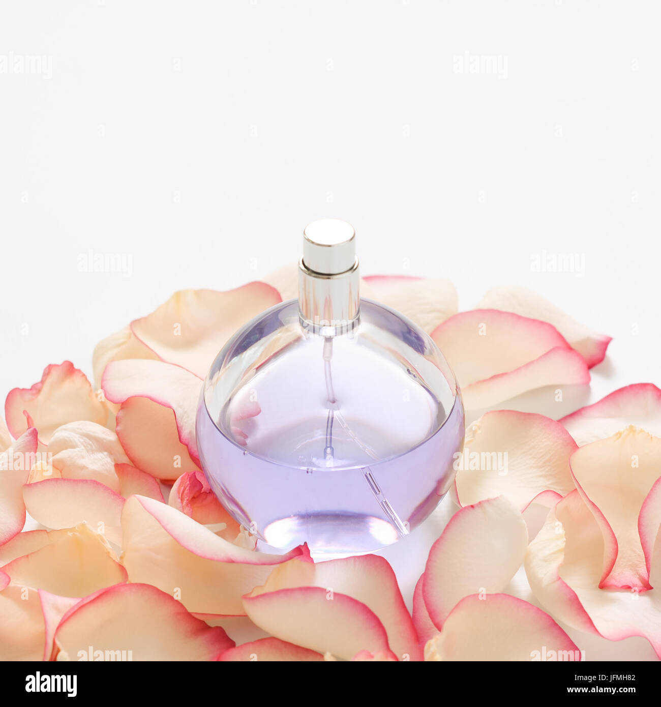 Perfume bottle with flower petals on light background. Perfumery ...