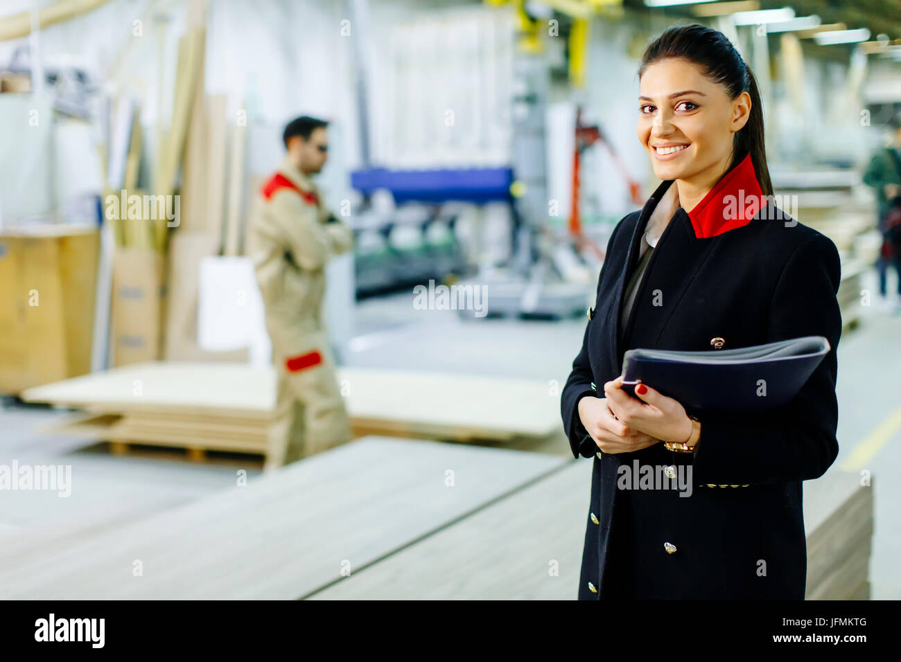 Pretty young woman holding file and controling process in the factory ...