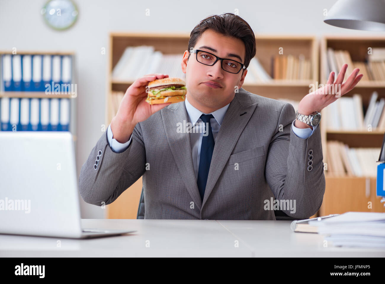 Hungry funny businessman eating junk food sandwich Stock Photo - Alamy