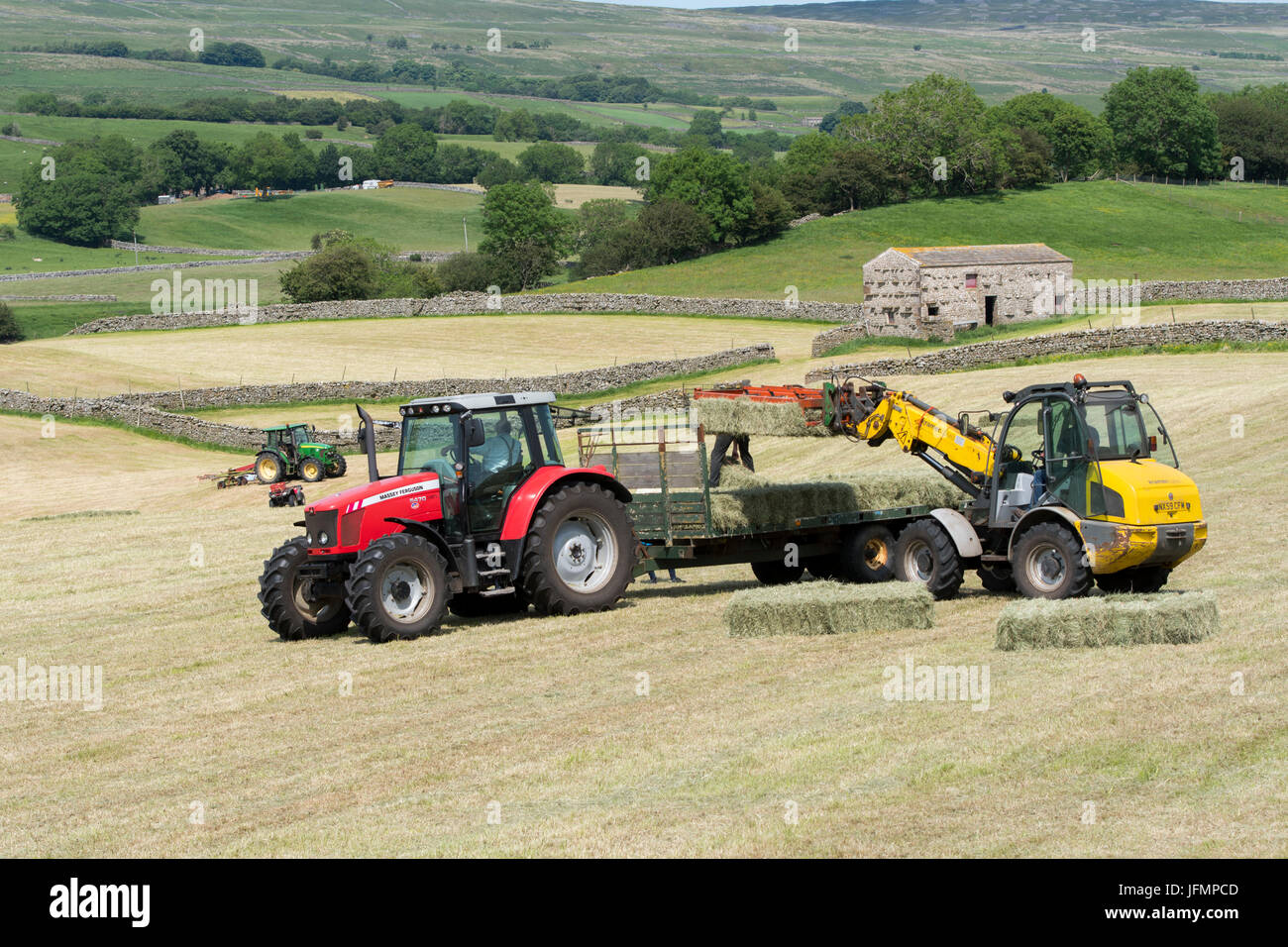 Picking up small bales of hay in upland meadow in Wensleydale, using a ...