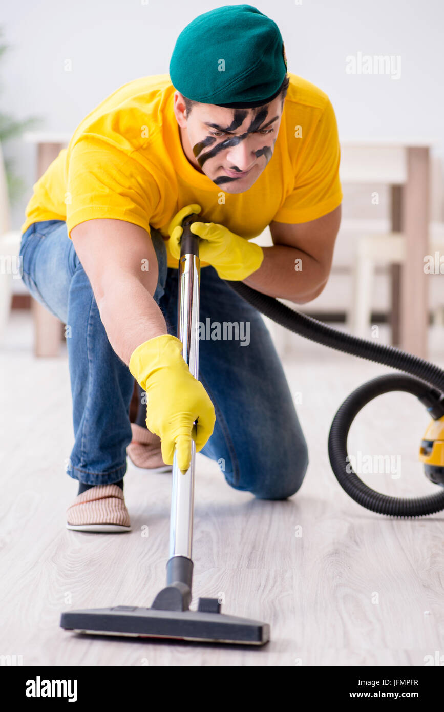 Funny man in military style cleaning the house Stock Photo - Alamy