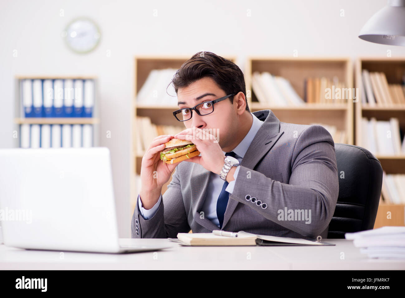 Hungry funny businessman eating junk food sandwich Stock Photo - Alamy