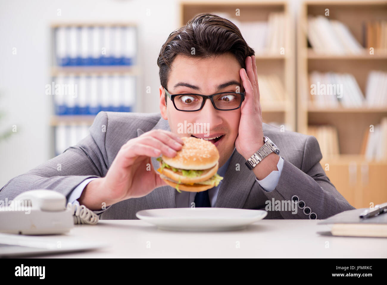 Hungry funny businessman eating junk food sandwich Stock Photo - Alamy