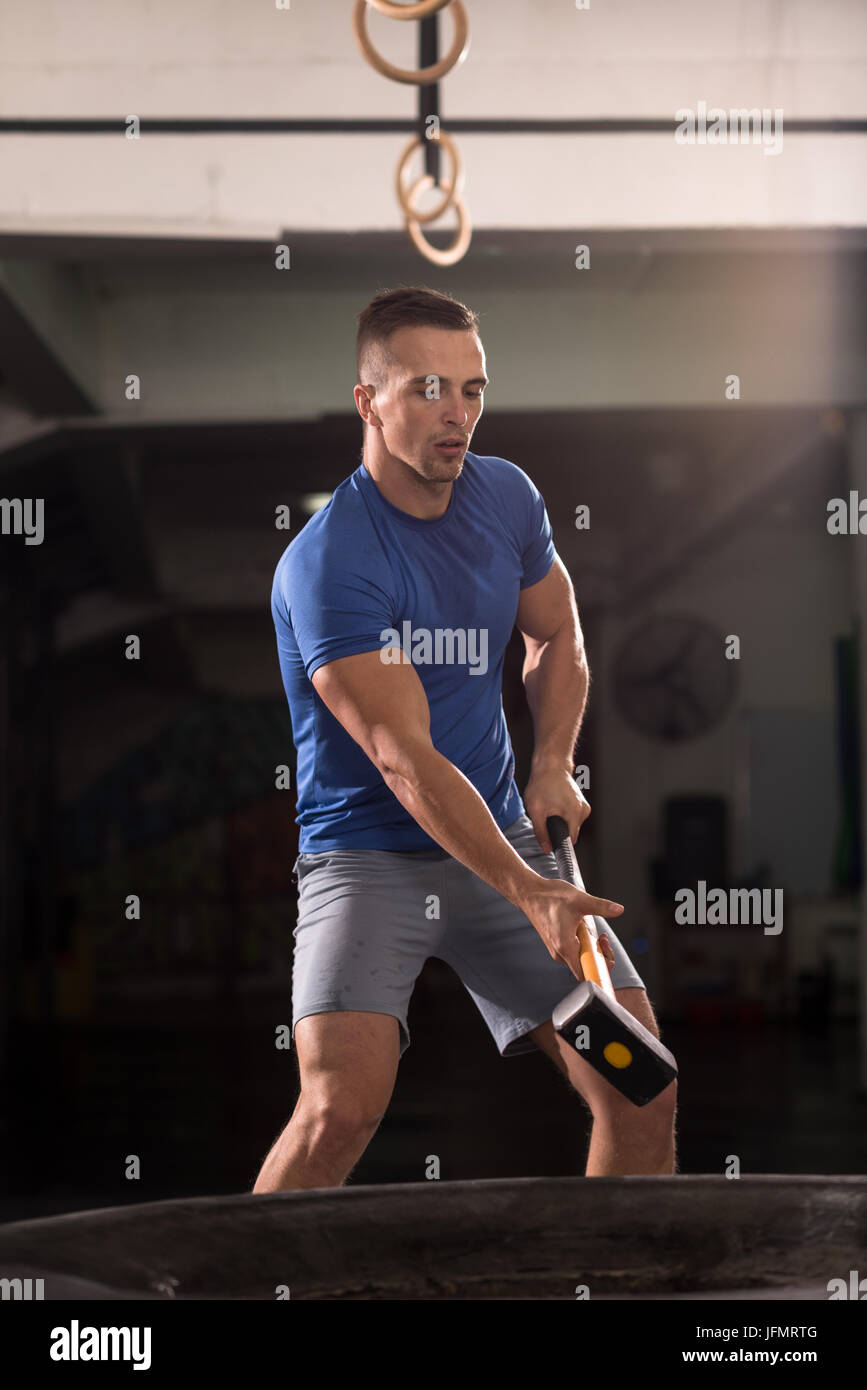 Sledgehammer Tire Hits young muscular man workout at gym with hammer ...