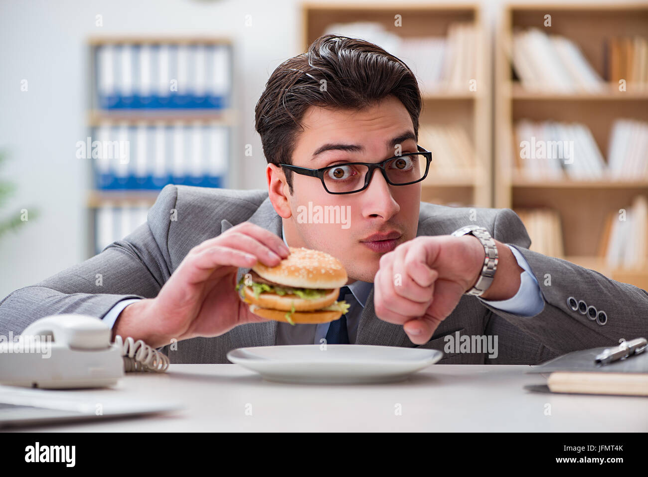Hungry funny businessman eating junk food sandwich Stock Photo - Alamy