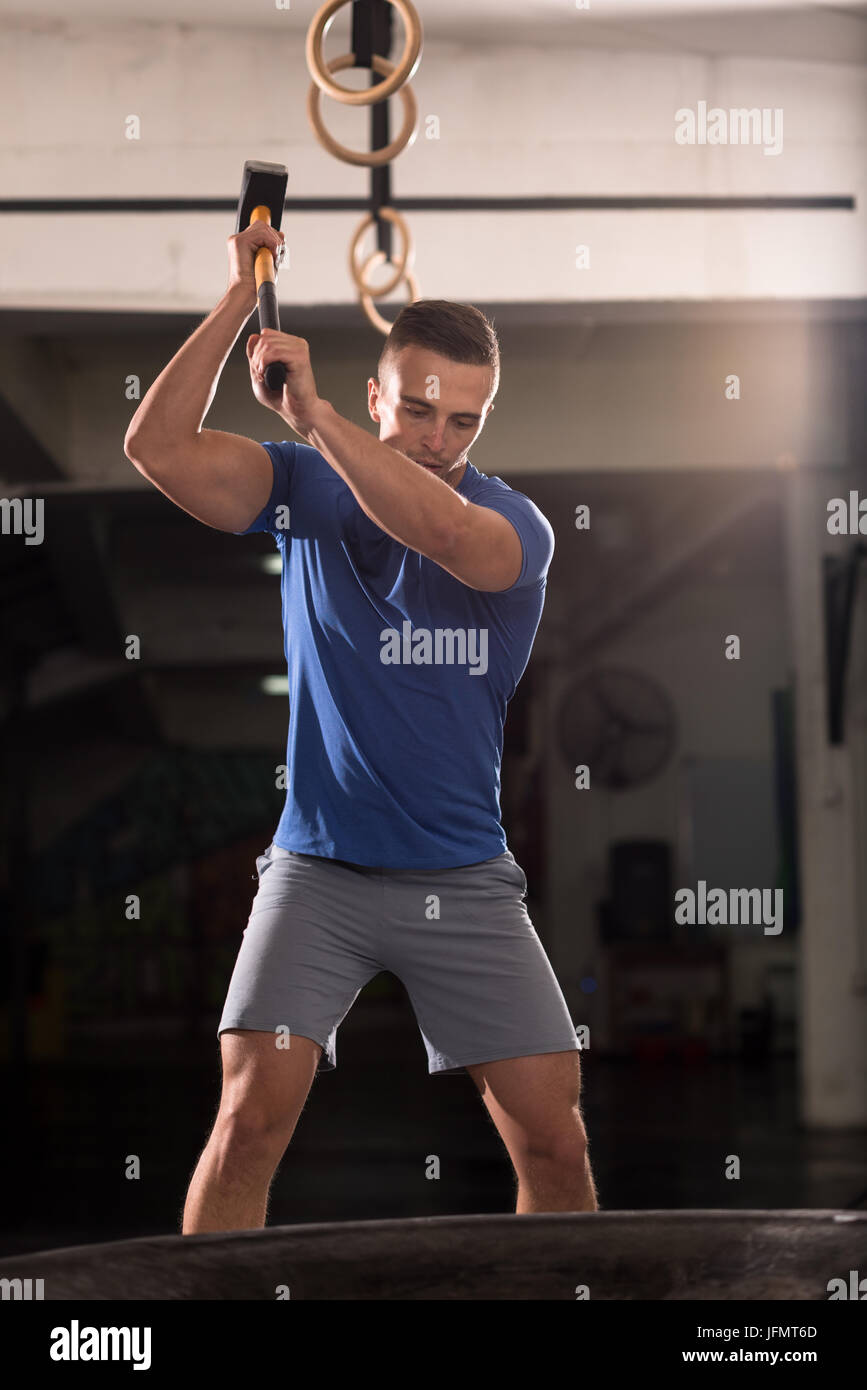 Sledgehammer Tire Hits young muscular man workout at gym with hammer ...