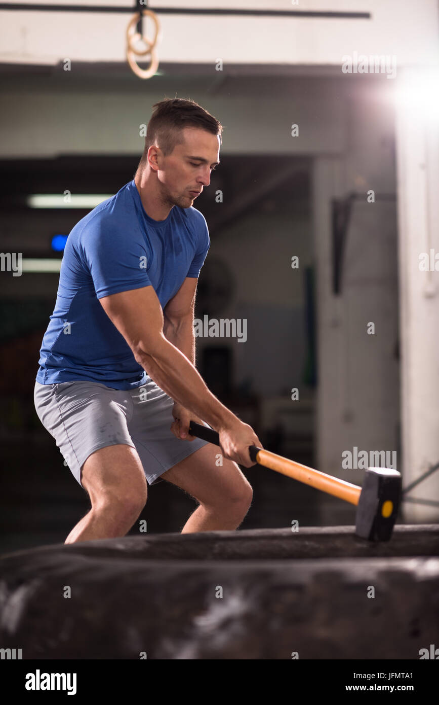 Sledgehammer Tire Hits young muscular man workout at gym with hammer ...