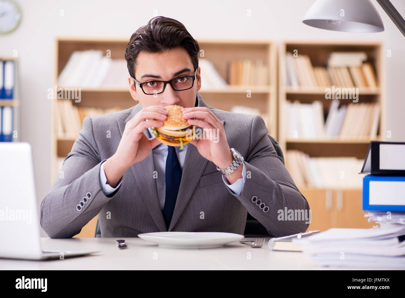 Hungry funny businessman eating junk food sandwich Stock Photo - Alamy