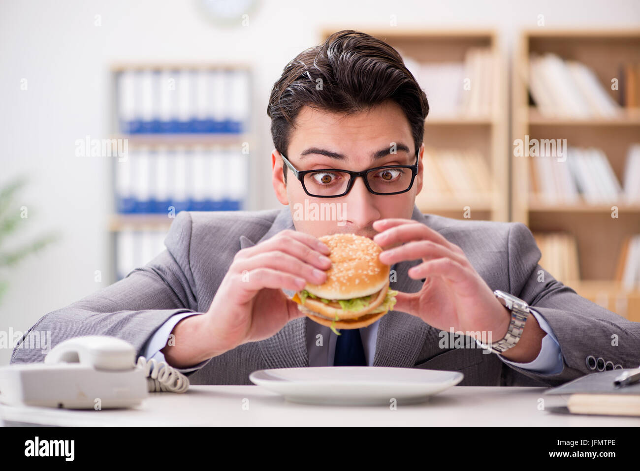 Hungry funny businessman eating junk food sandwich Stock Photo - Alamy