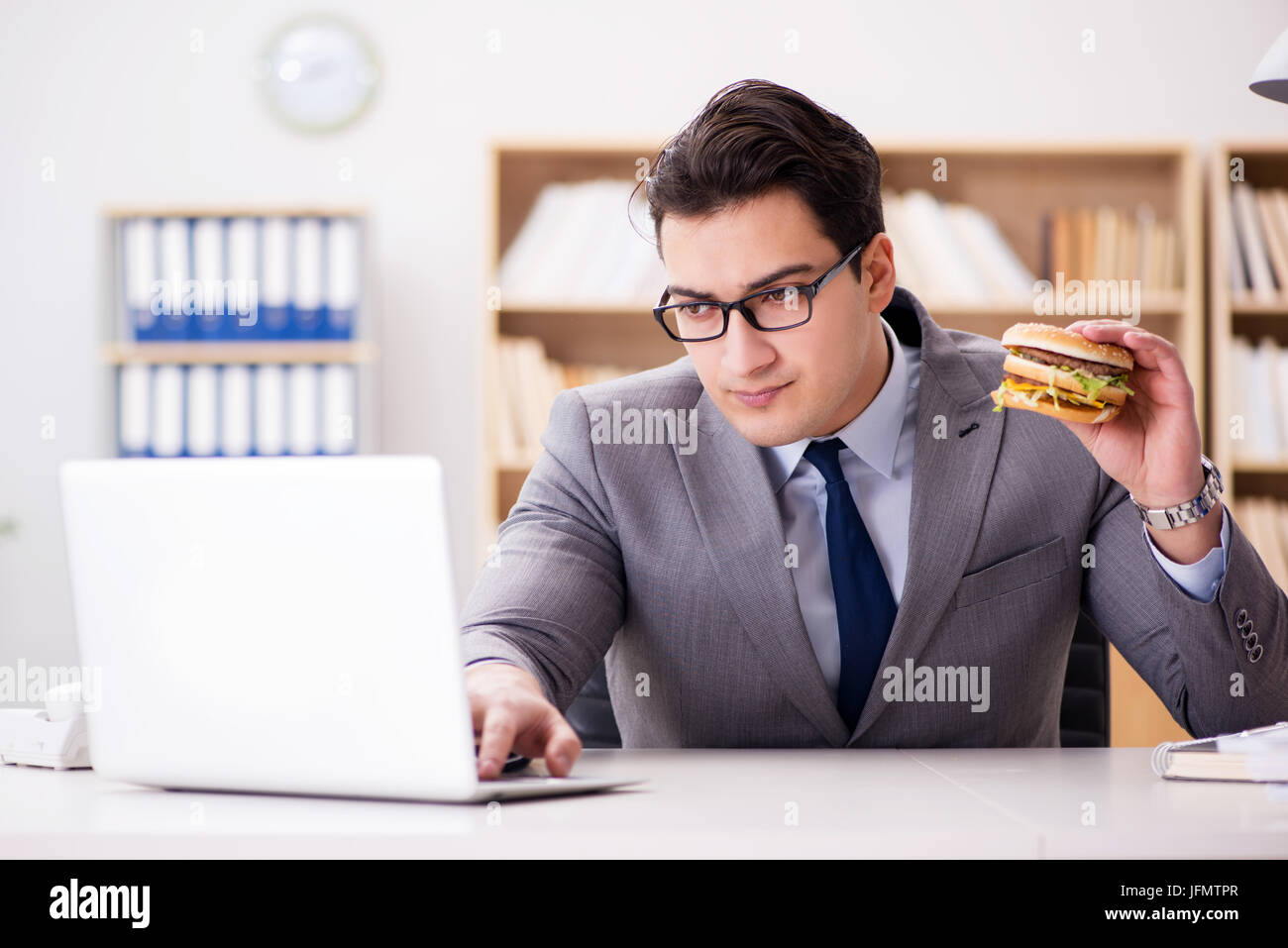 Hungry funny businessman eating junk food sandwich Stock Photo - Alamy