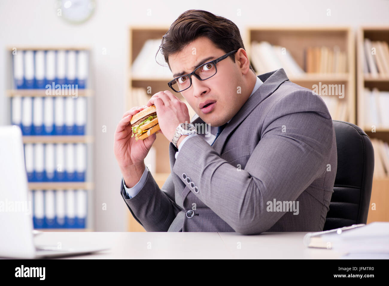 Hungry funny businessman eating junk food sandwich Stock Photo - Alamy