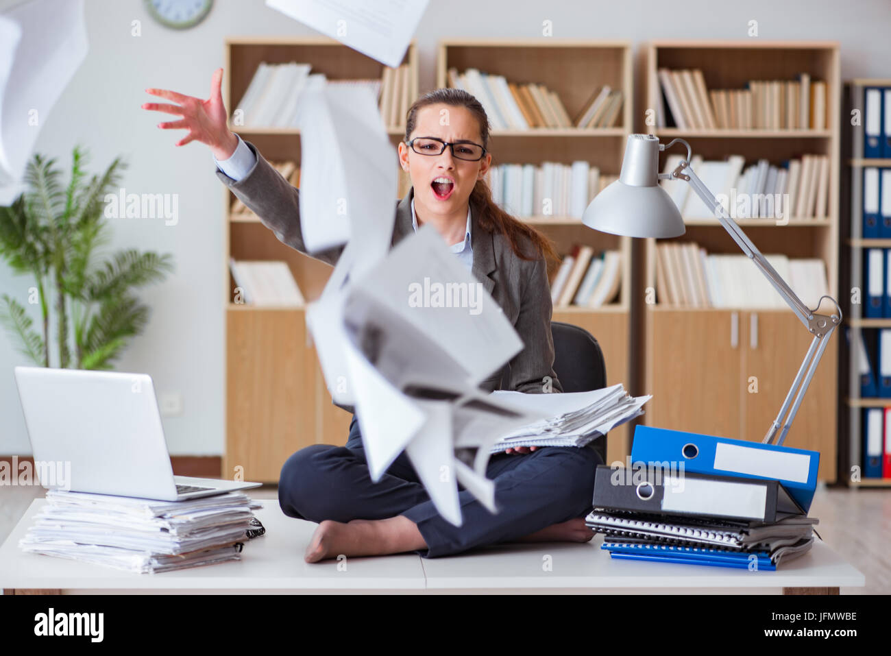 Busy angry businesswoman sitting on the desk in office Stock Photo - Alamy