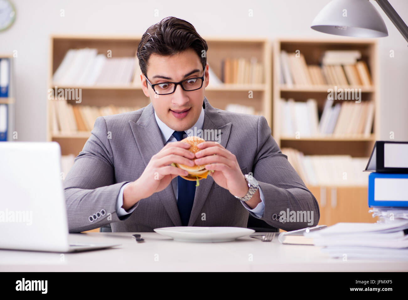 Hungry funny businessman eating junk food sandwich Stock Photo - Alamy