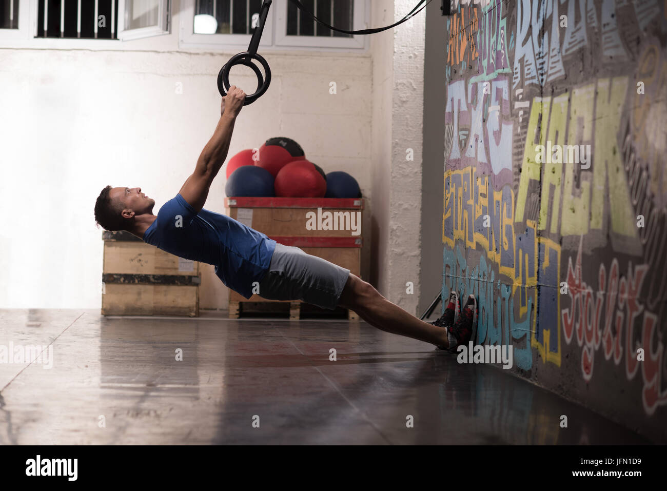 Fitness handsome man doing dipping exercise using rings in the gym ...