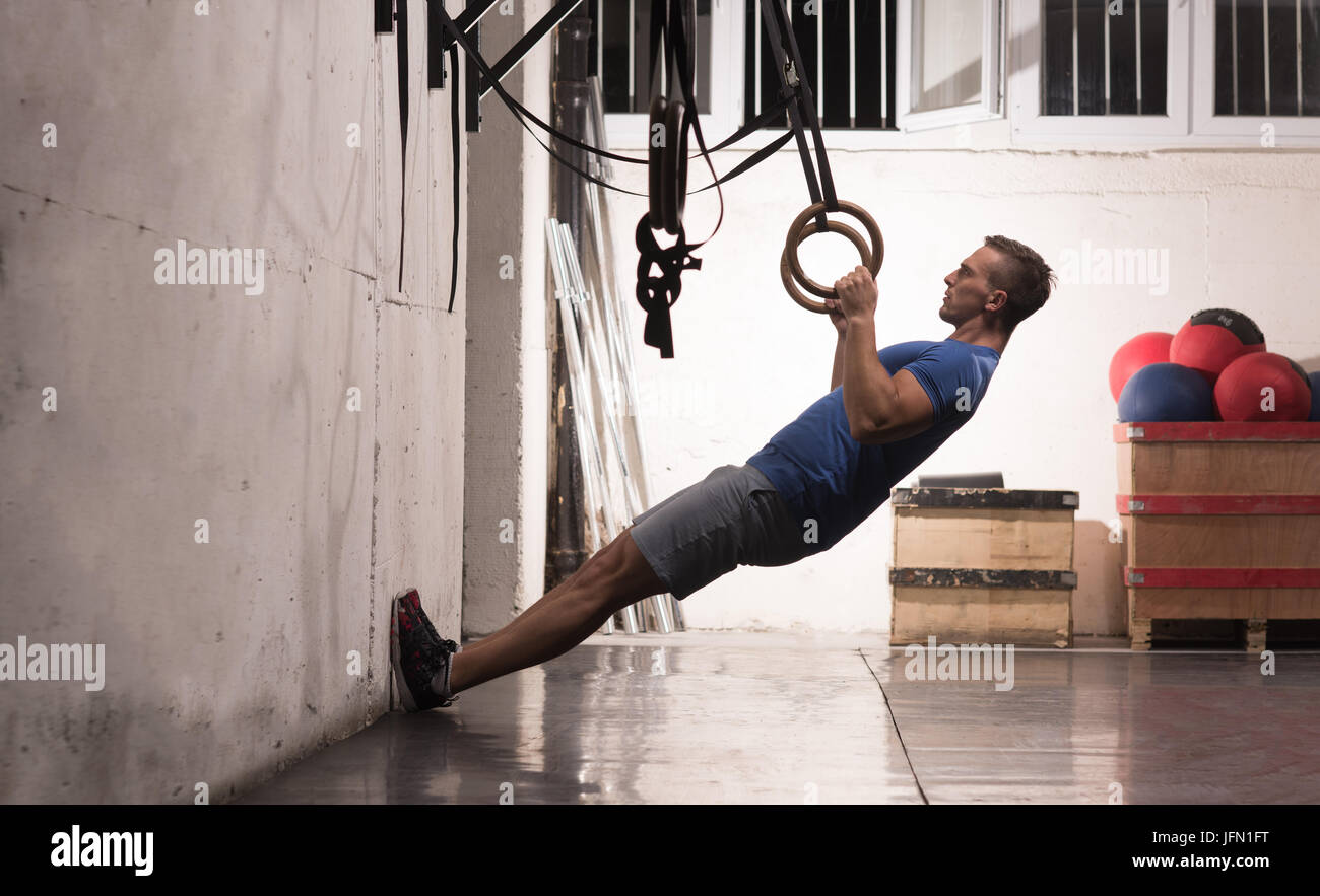 Fitness handsome man doing dipping exercise using rings in the gym ...