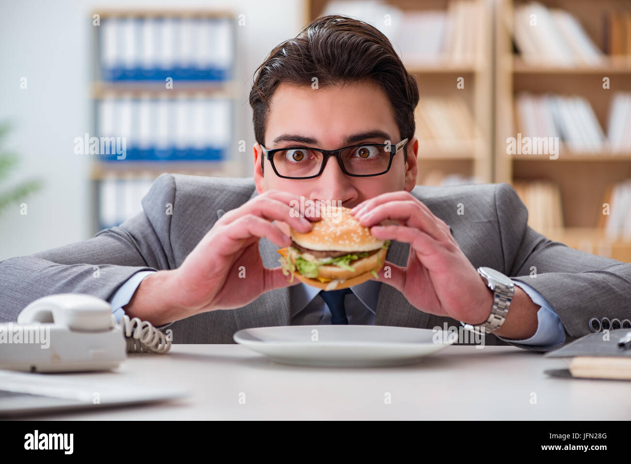 The hungry funny businessman eating junk food sandwich Stock Photo - Alamy