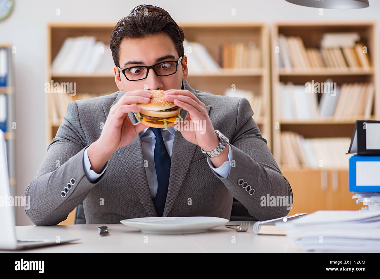 The hungry funny businessman eating junk food sandwich Stock Photo - Alamy