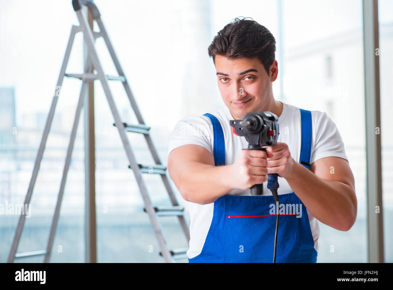 The young worker with hand drill Stock Photo - Alamy