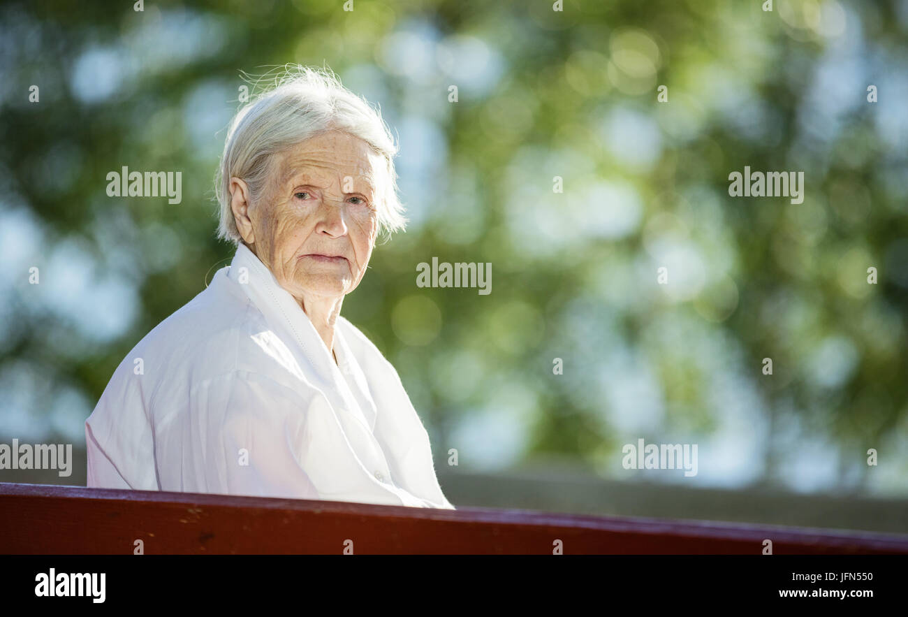 Portrait of senior woman sitting on bench in summer park Stock Photo ...