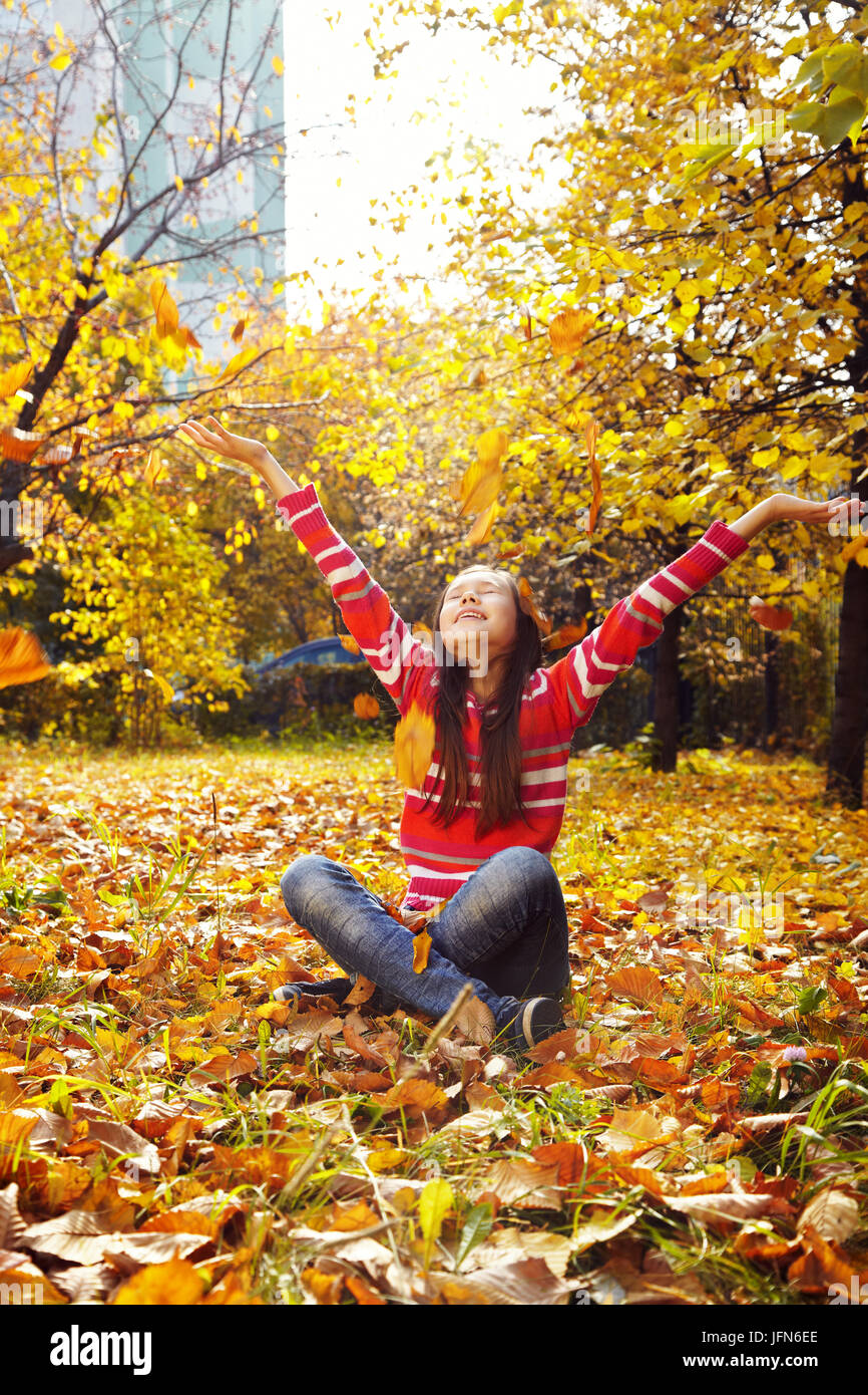 happy teenage girl in an autumn park. woman throwing up yellow leaves ...