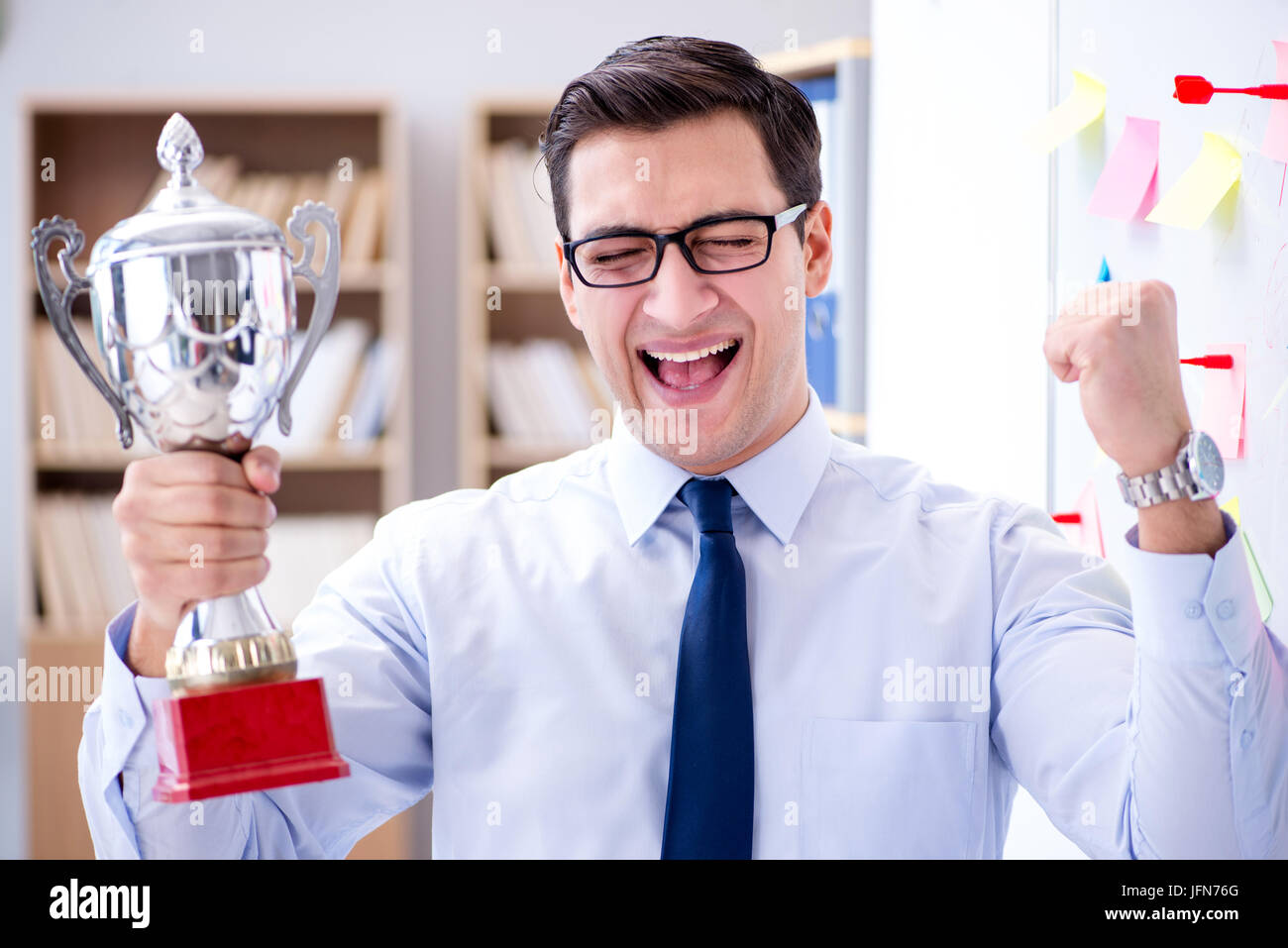 Young businessman receiving prize cup in office Stock Photo - Alamy